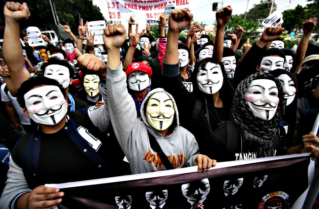 Filipino student protesters wearing masks raise their clenched f ...